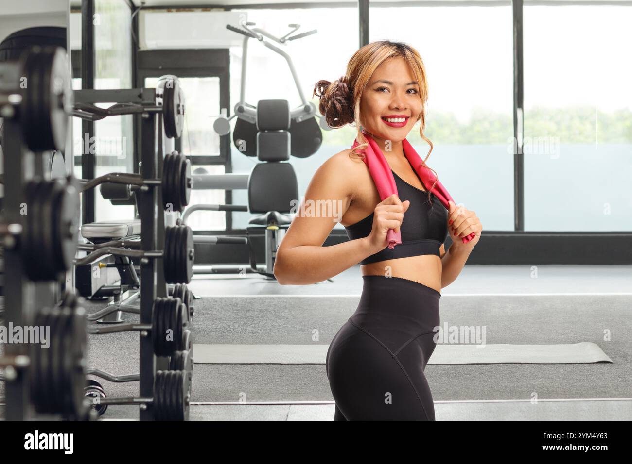 Fit young filipina woman in sportswear holding a towel at a gym Stock ...