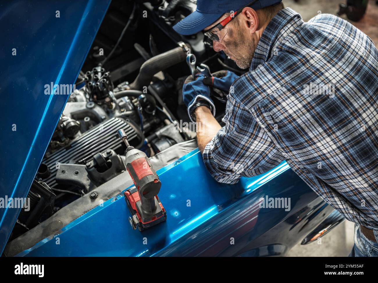 A mechanic works diligently on an engine inside a well-lit workshop ...