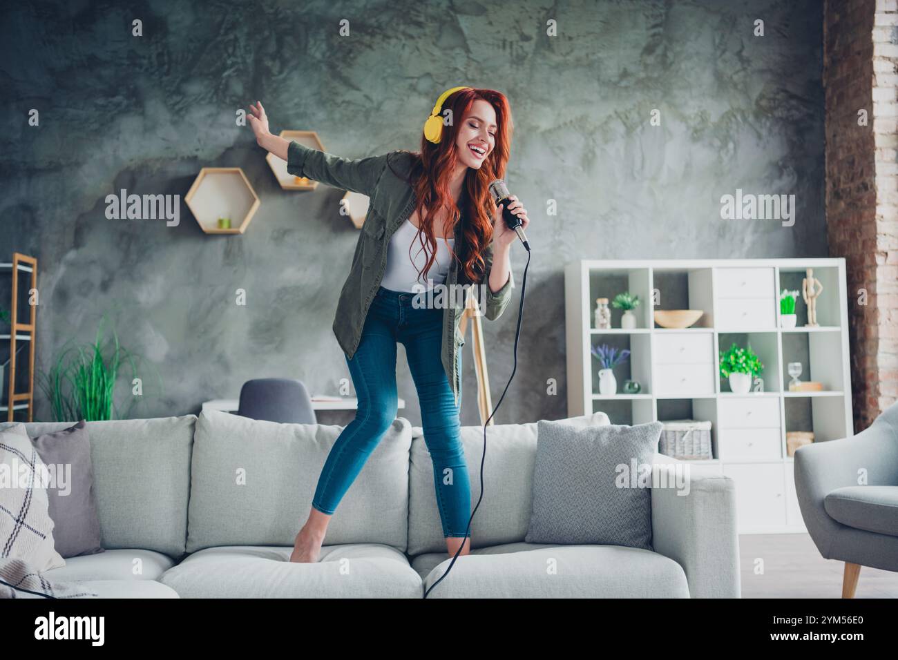 Full size photo of attractive ginger woman stand sofa sing karaoke ...