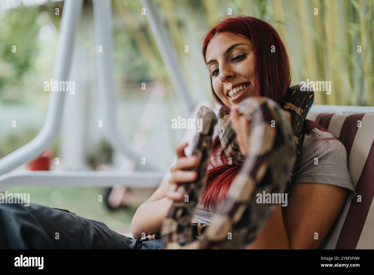 Girl with red hair happily holding a friendly pet snake outdoors Stock ...