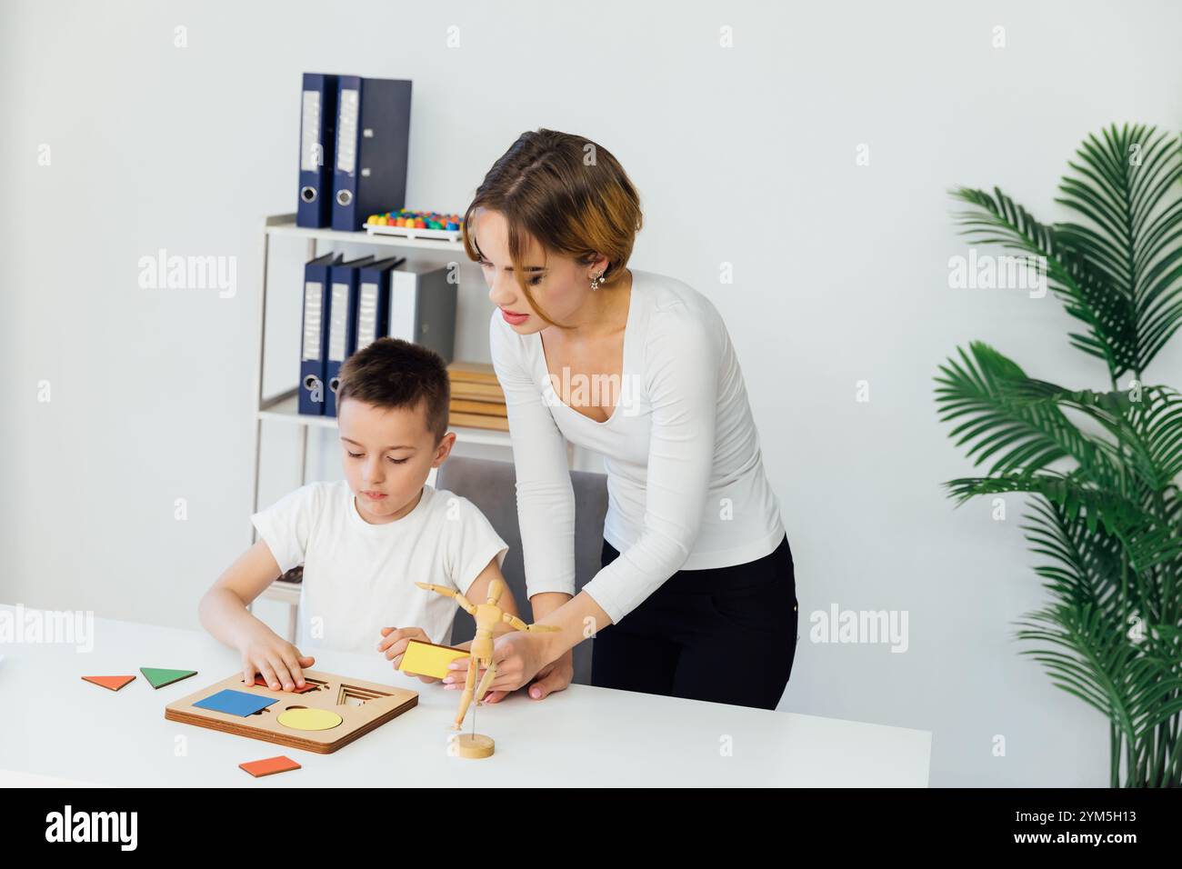 A female teacher conducts developmental training sessions with a boy ...