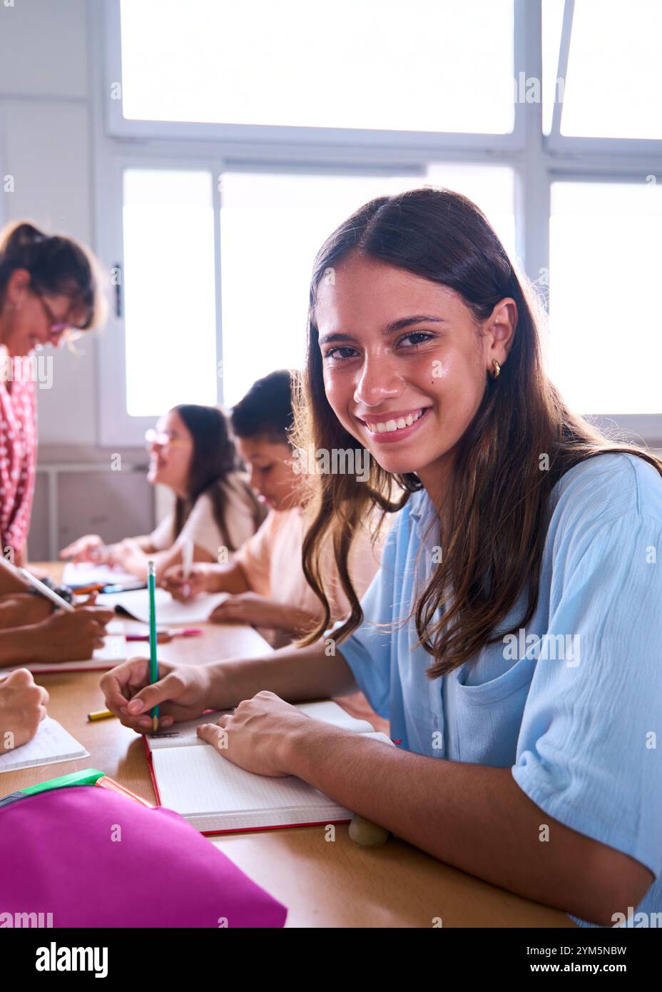 Portrait cheerful Caucasian girl primary school student sitting at desk ...
