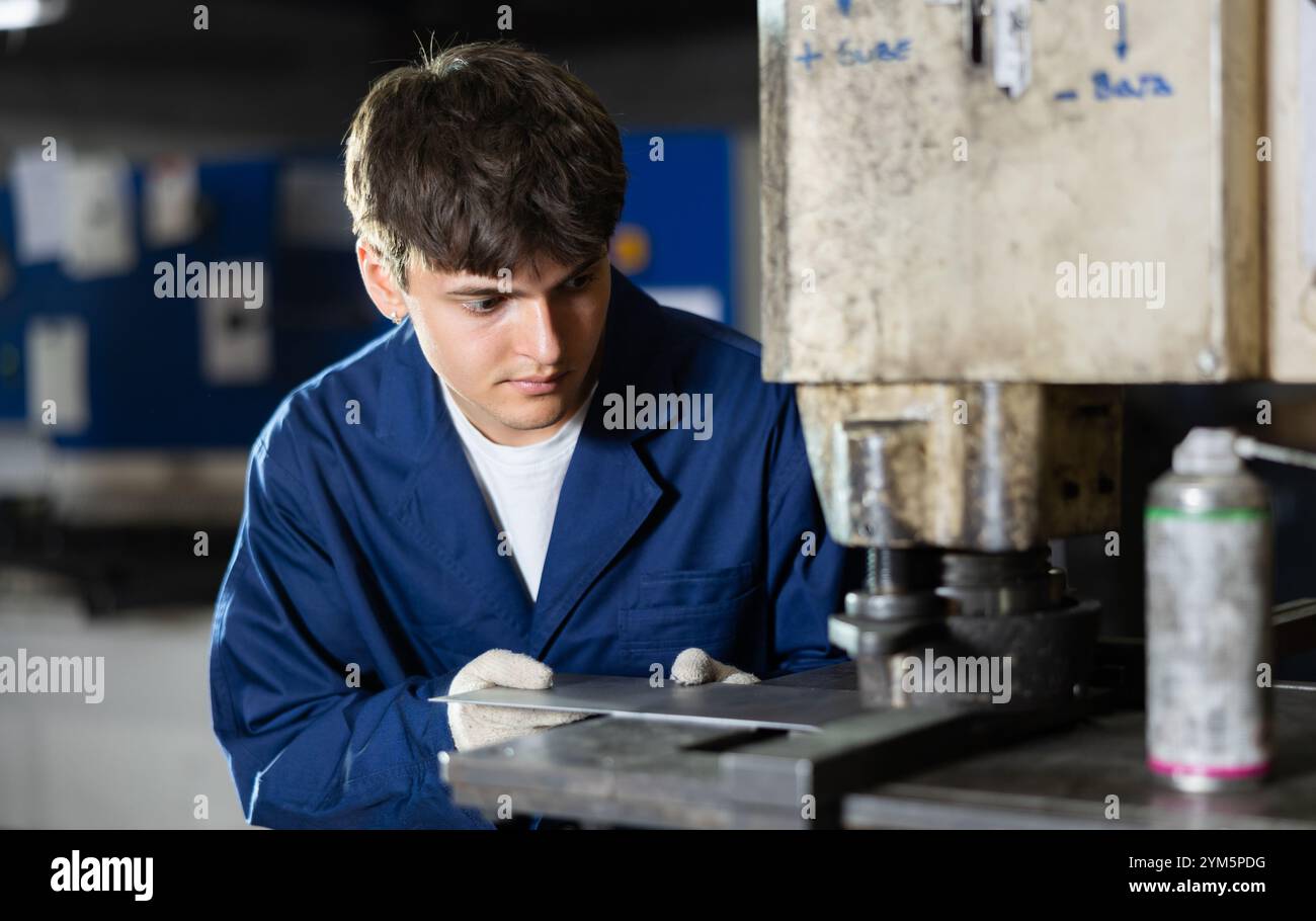 Young worker working on a hydraulic press - punching holes in metal ...
