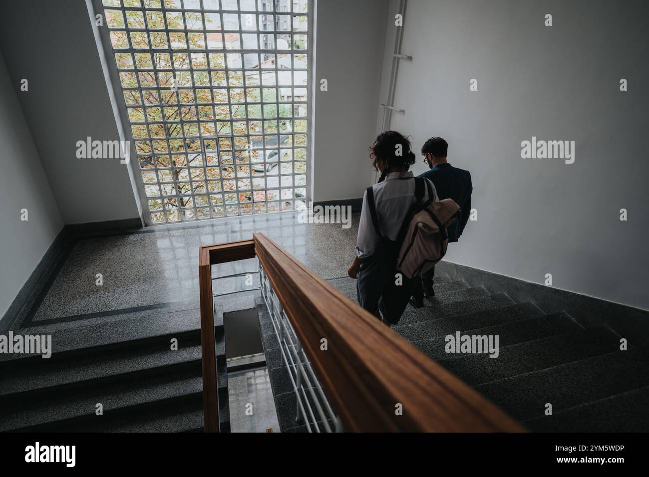 Two students walking down staircase in school building Stock Photo - Alamy