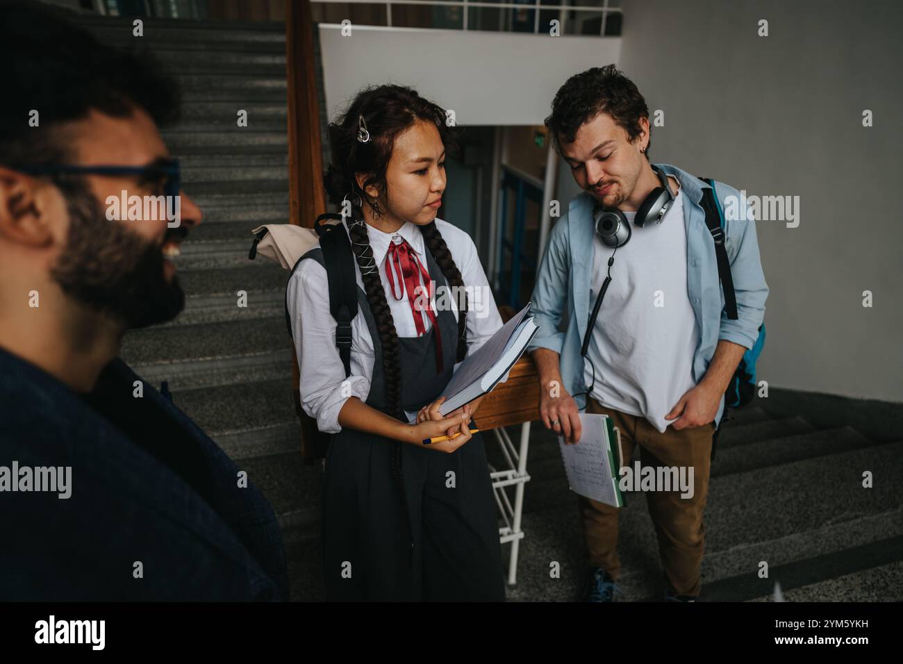 Three students discussing notes on a stairwell Stock Photo - Alamy