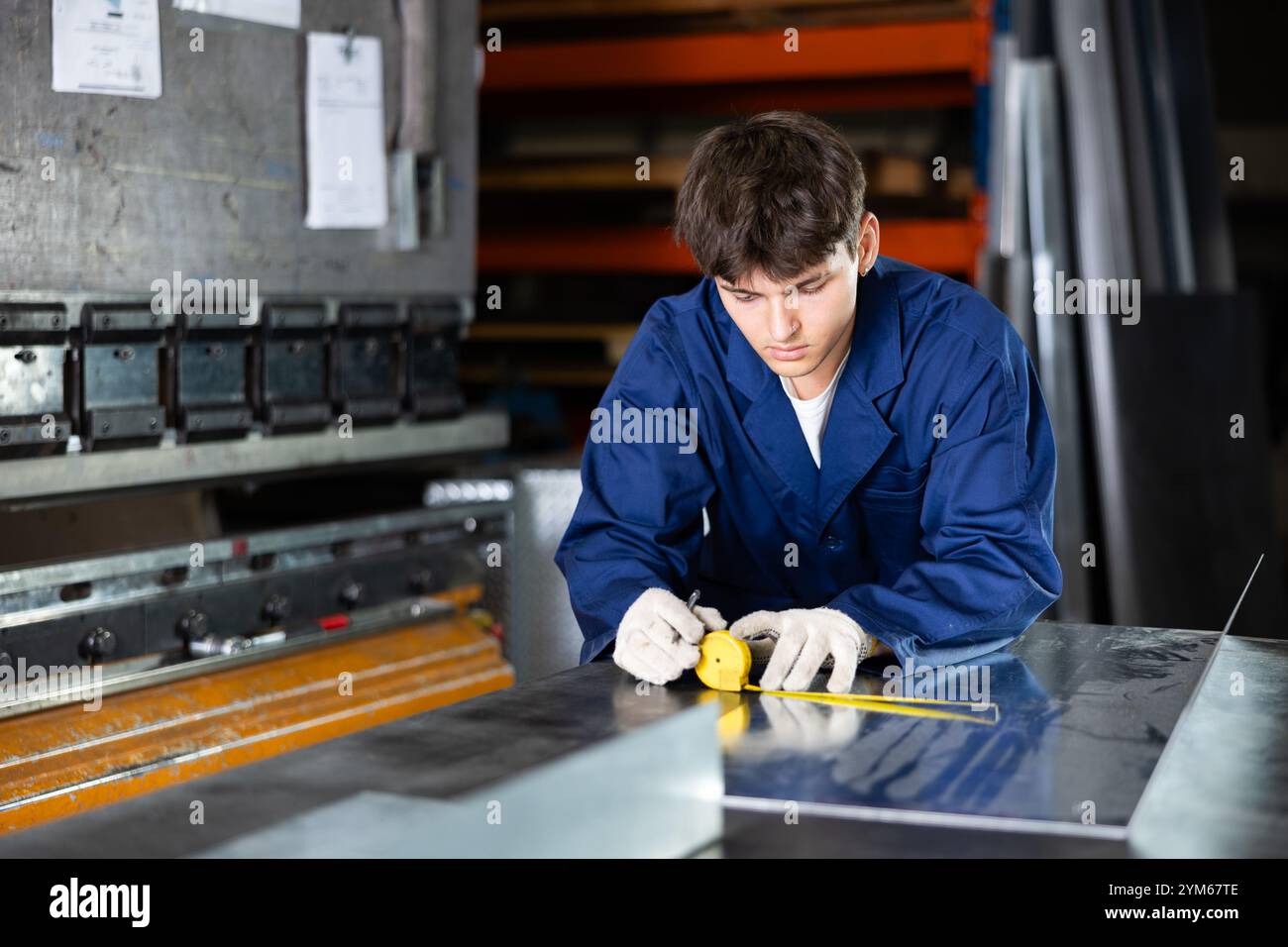 Guy measuring sheet of metal with tape measure Stock Photo - Alamy
