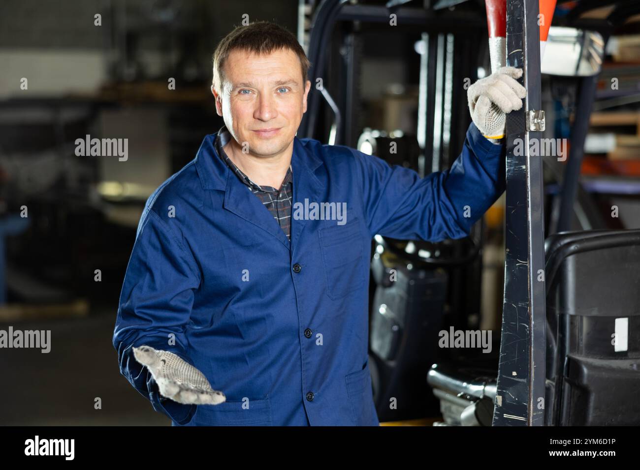 Smiling forklift operator standing beside vehicle in warehouse Stock ...