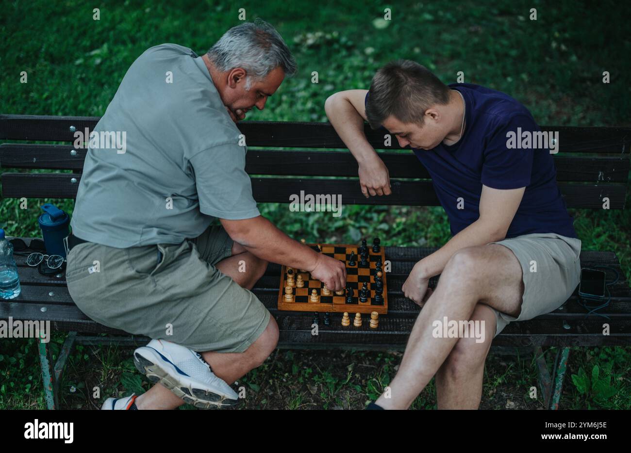 Father and son playing chess on a park bench outdoors Stock Photo - Alamy