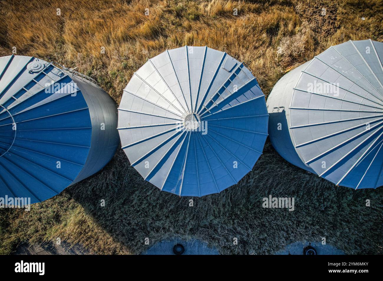 Three metal grain silos are shown in the image, with one of them having ...