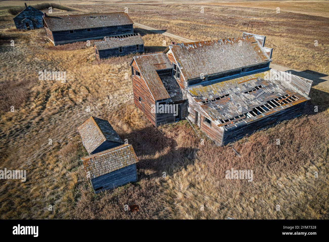 A group of old, abandoned buildings in a field. The buildings are in ...