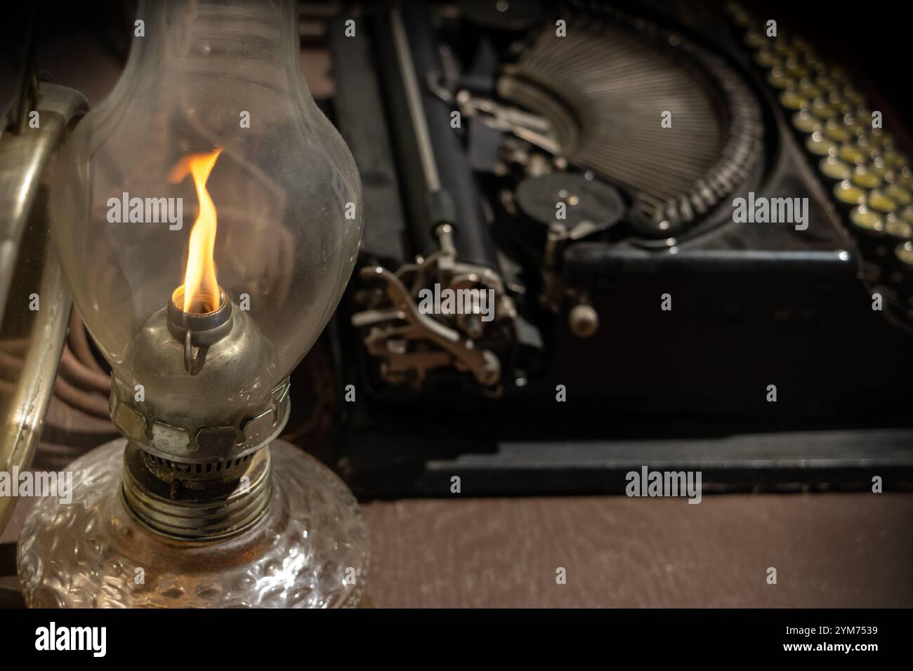 An oil lamp is lit on a table with a vintage typewriter Stock Photo - Alamy