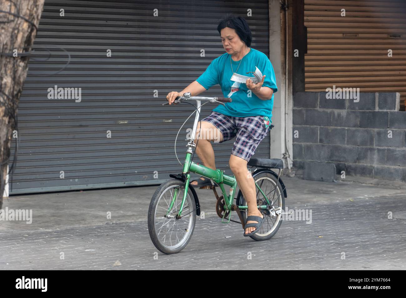 BANGKOK, THAILAND, MAR 09 2024, A woman rides a bicycle on the sidewalk ...