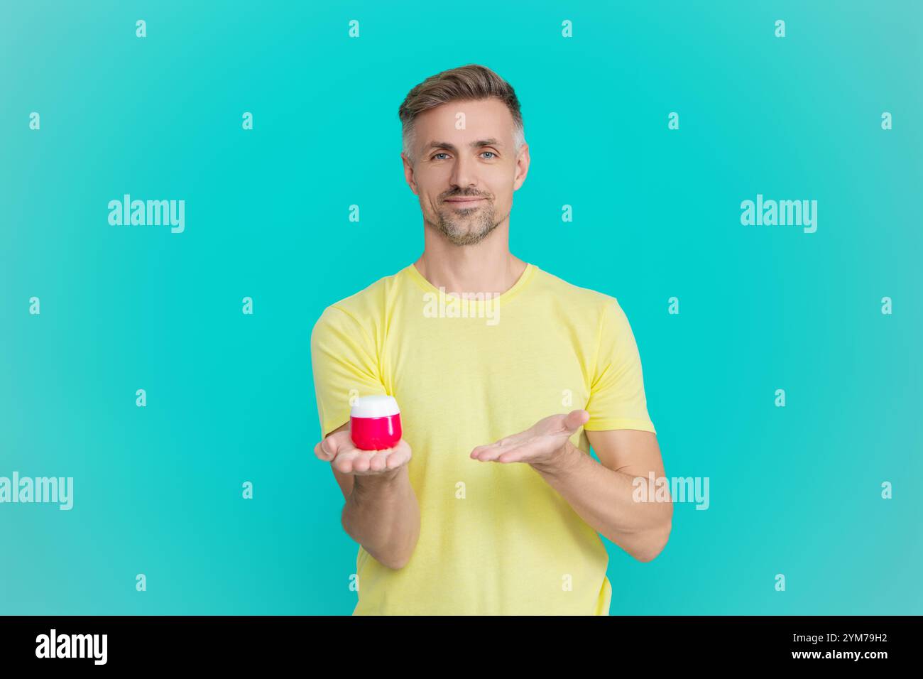 Man showing face cream isolated on blue. Mature man hold skin cream ...