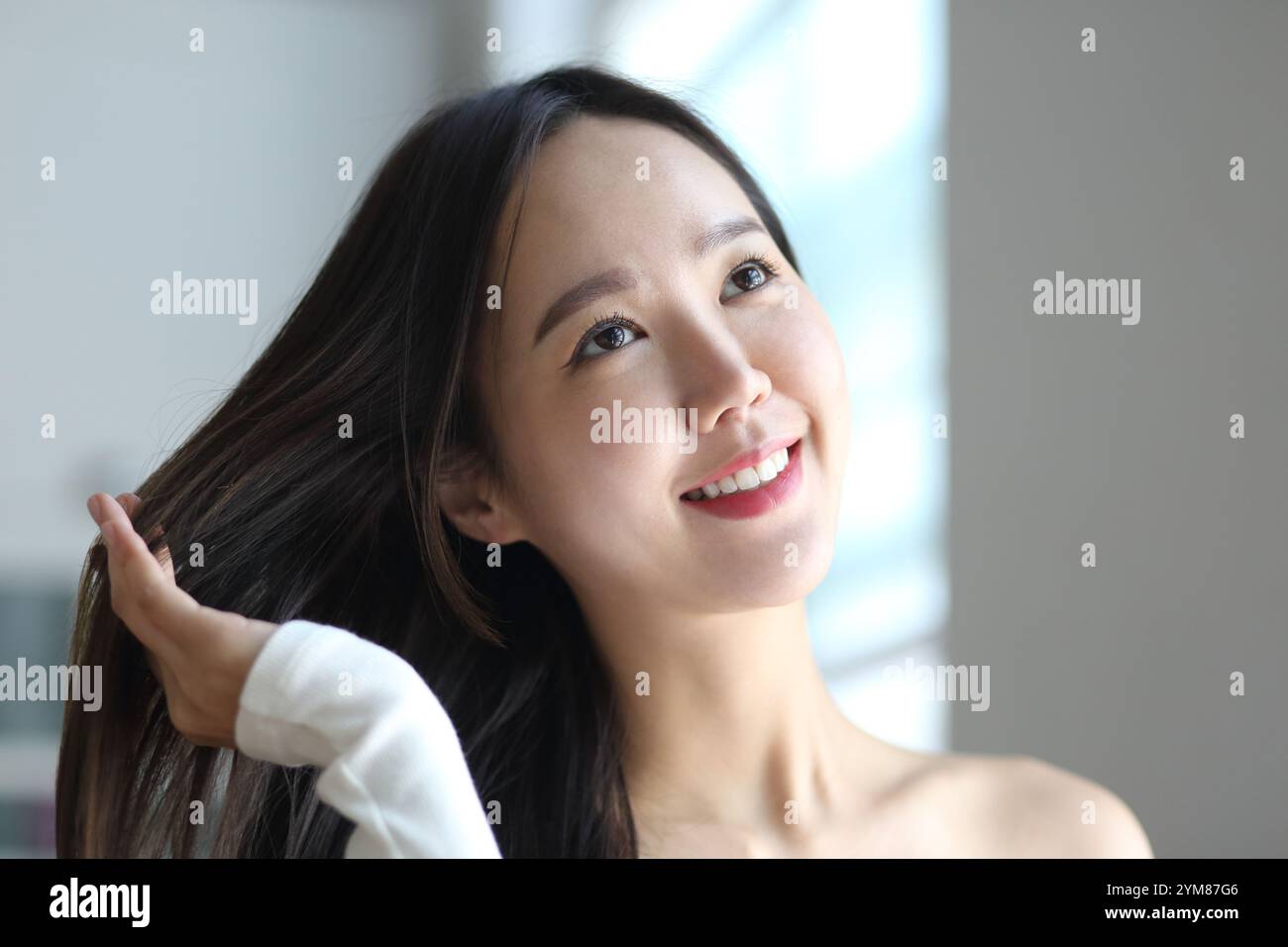 Smiling young woman stroking her own hair Stock Photo - Alamy