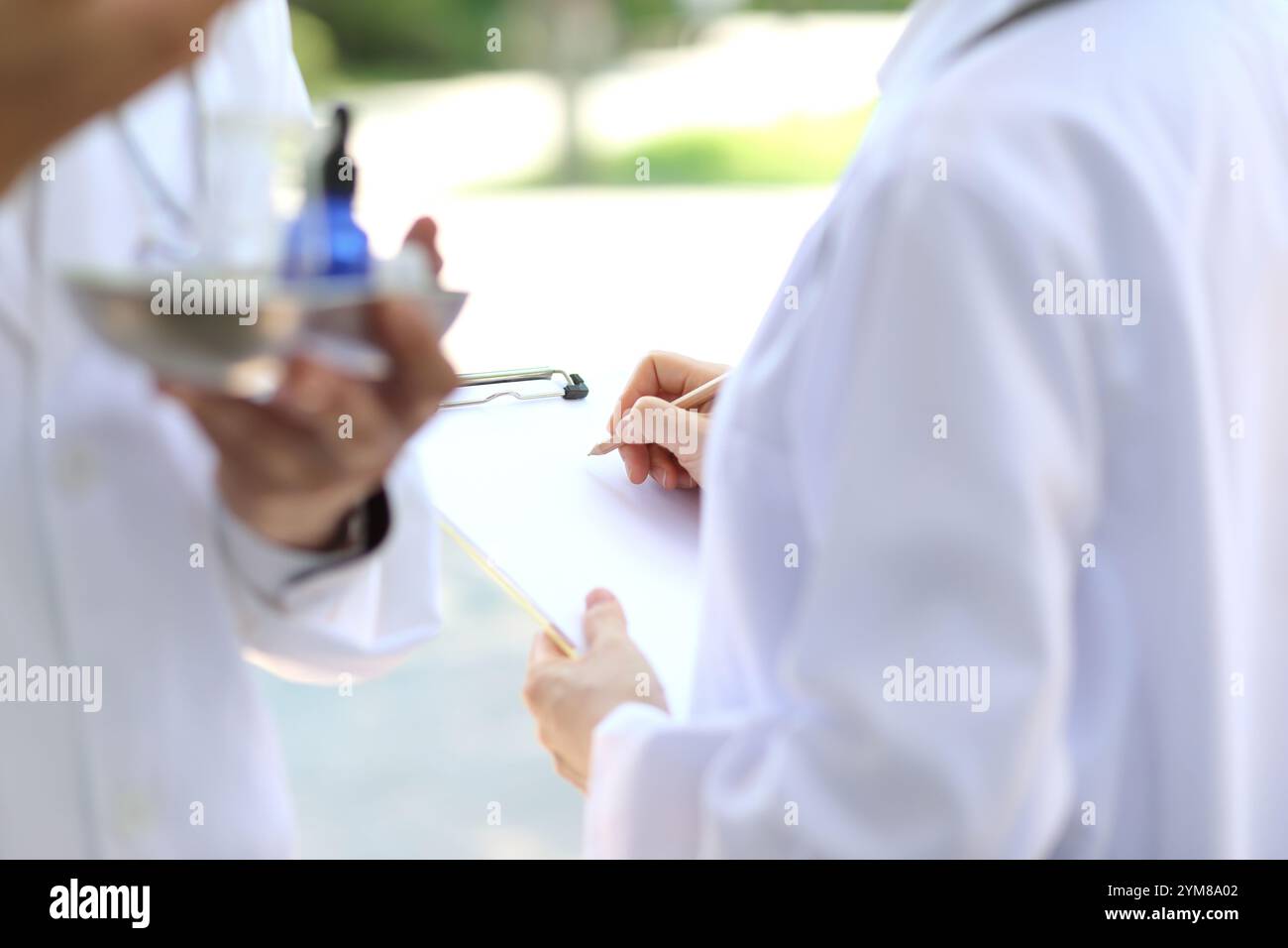 Female doctor making notes in chart Stock Photo - Alamy