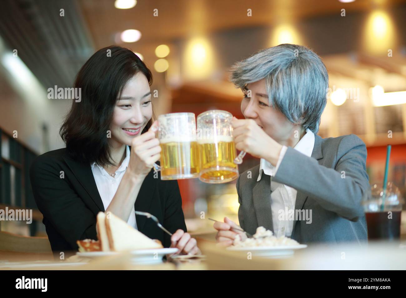 Two women making a toast at a restaurant Stock Photo - Alamy