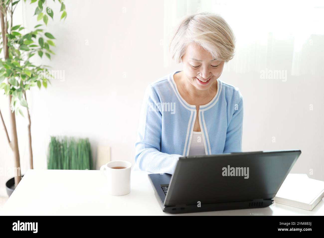 Older person operating a laptop computer with a smile Stock Photo - Alamy