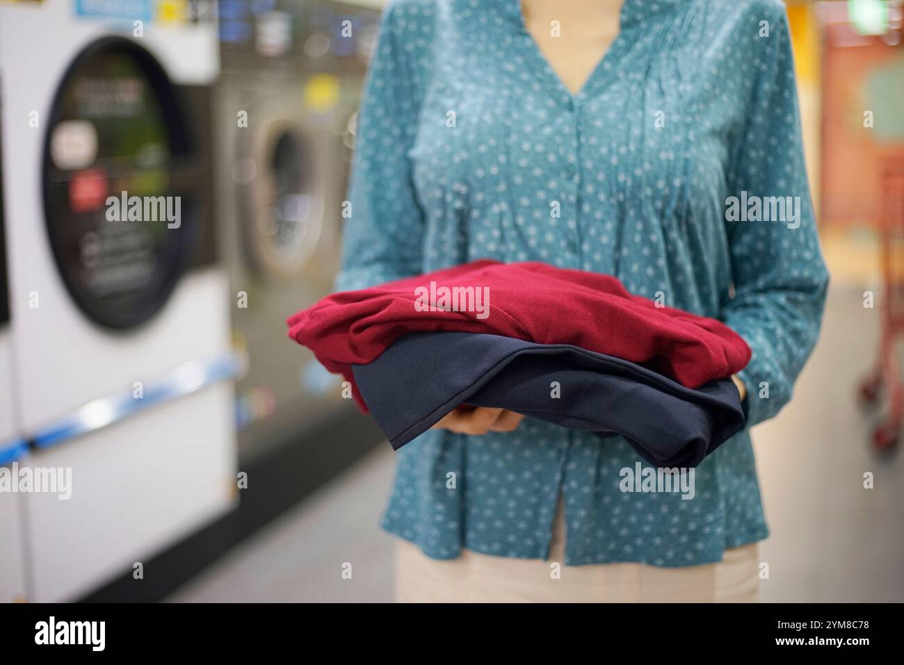 Woman holding laundry at coin-operated laundromat Stock Photo - Alamy