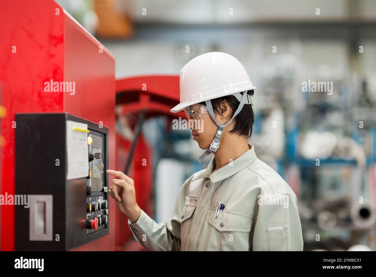 Man in work clothes operating a machine Stock Photo - Alamy