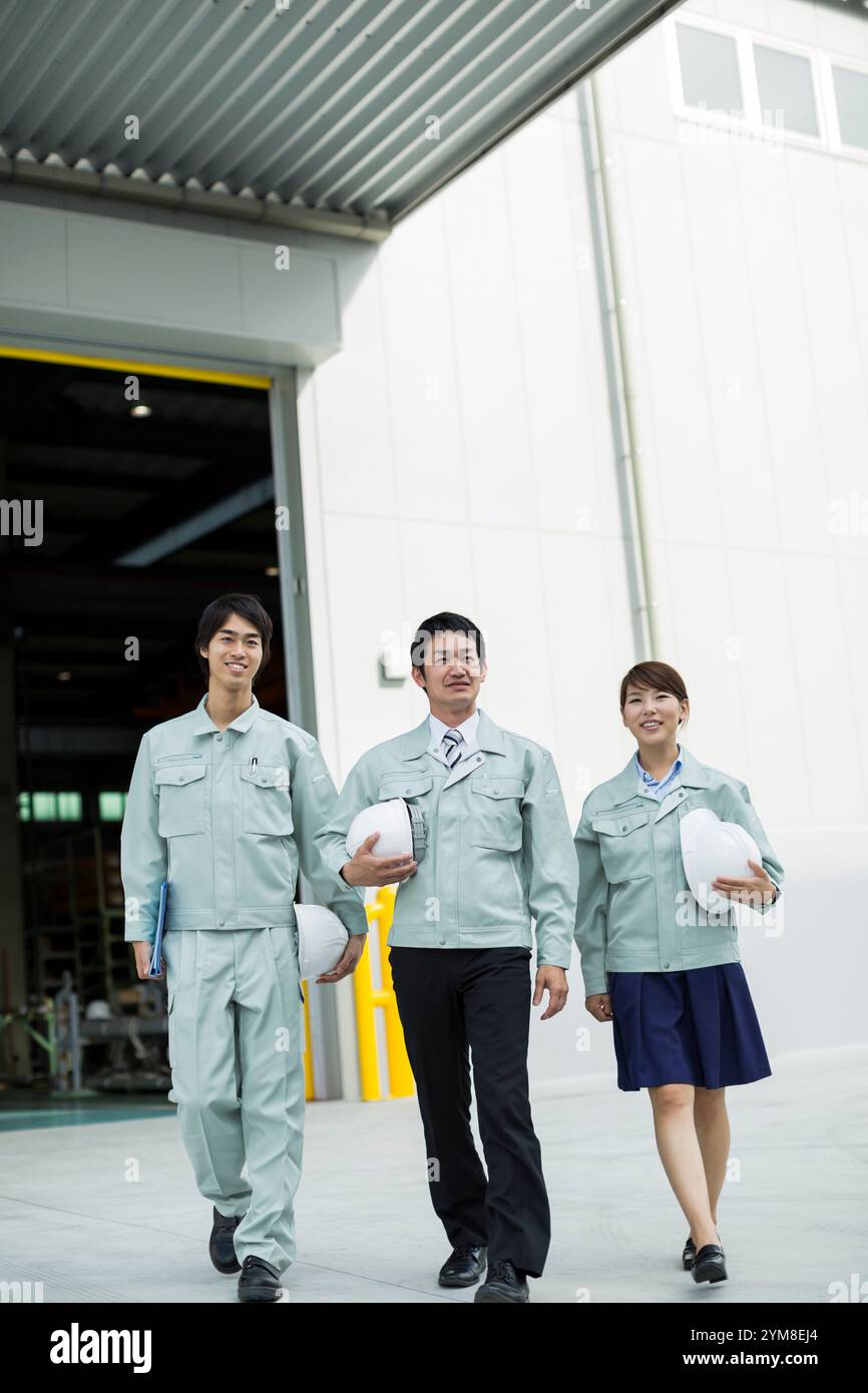Male and female workers walking with helmets Stock Photo - Alamy
