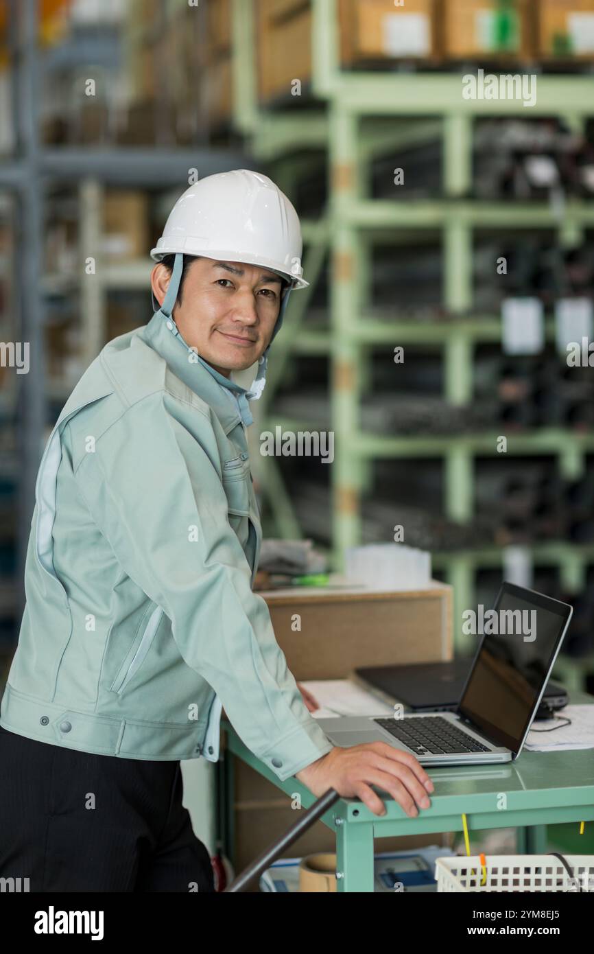 Man in work clothes working in a factory Stock Photo - Alamy