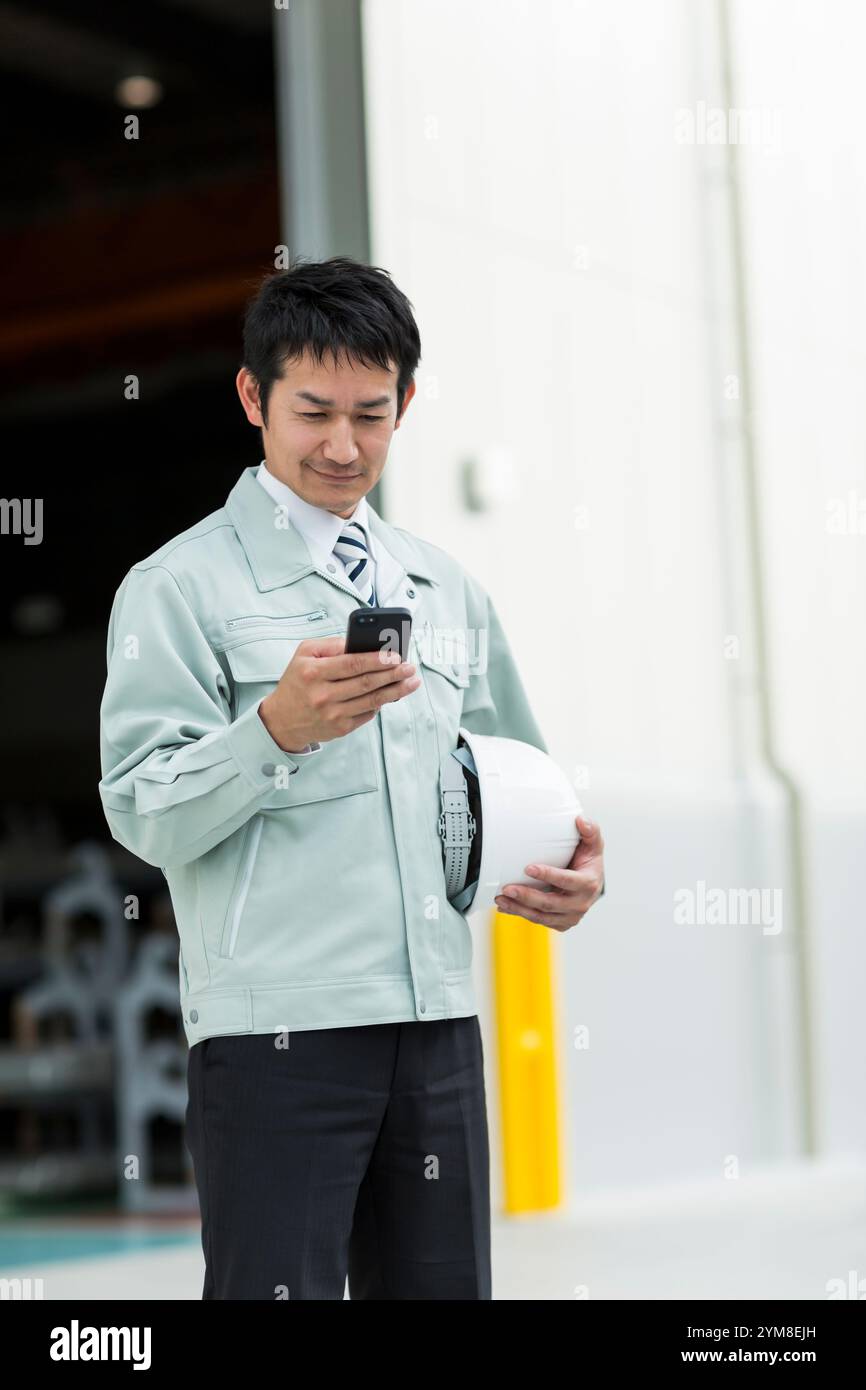 Man in work clothes operating a smartphone Stock Photo - Alamy