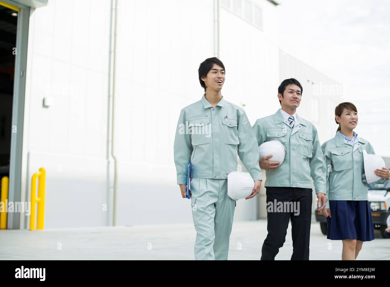 Male and female workers walking with helmets Stock Photo - Alamy