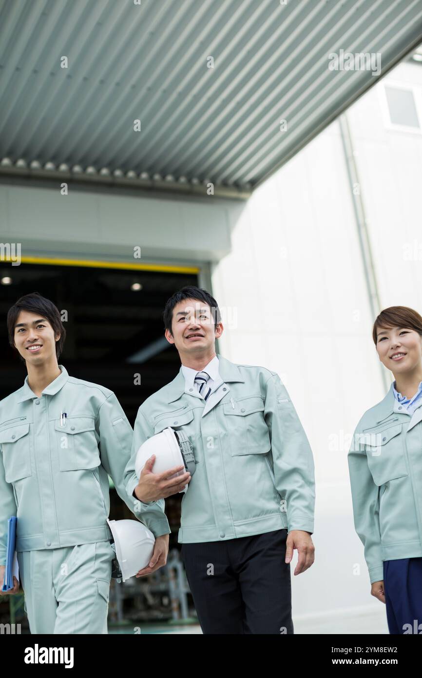 Male and female workers walking with helmets Stock Photo - Alamy