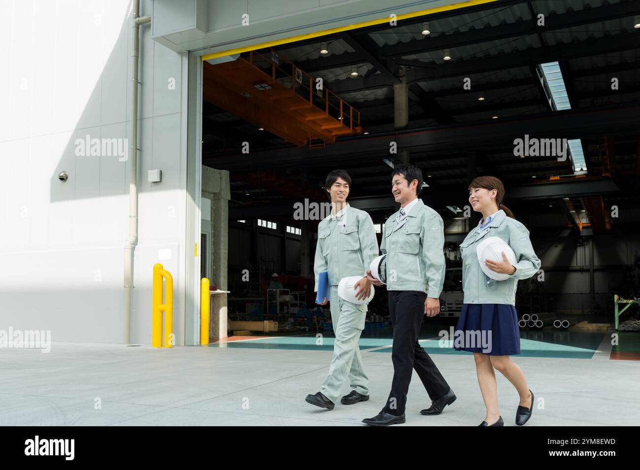 Male and female workers walking with helmets Stock Photo - Alamy