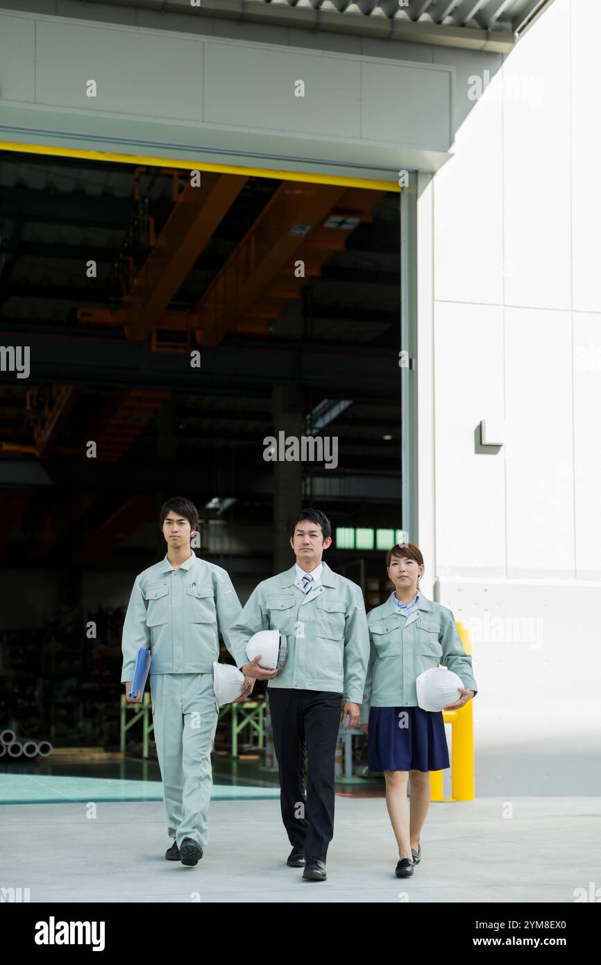 Male and female workers walking with helmets Stock Photo - Alamy