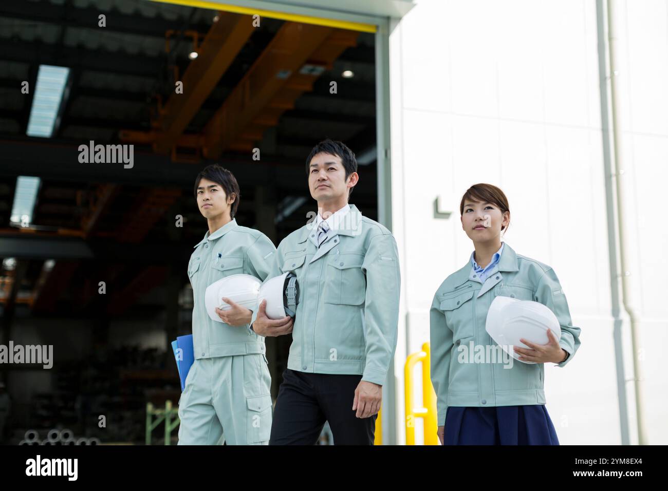 Male and female workers walking with helmets Stock Photo - Alamy