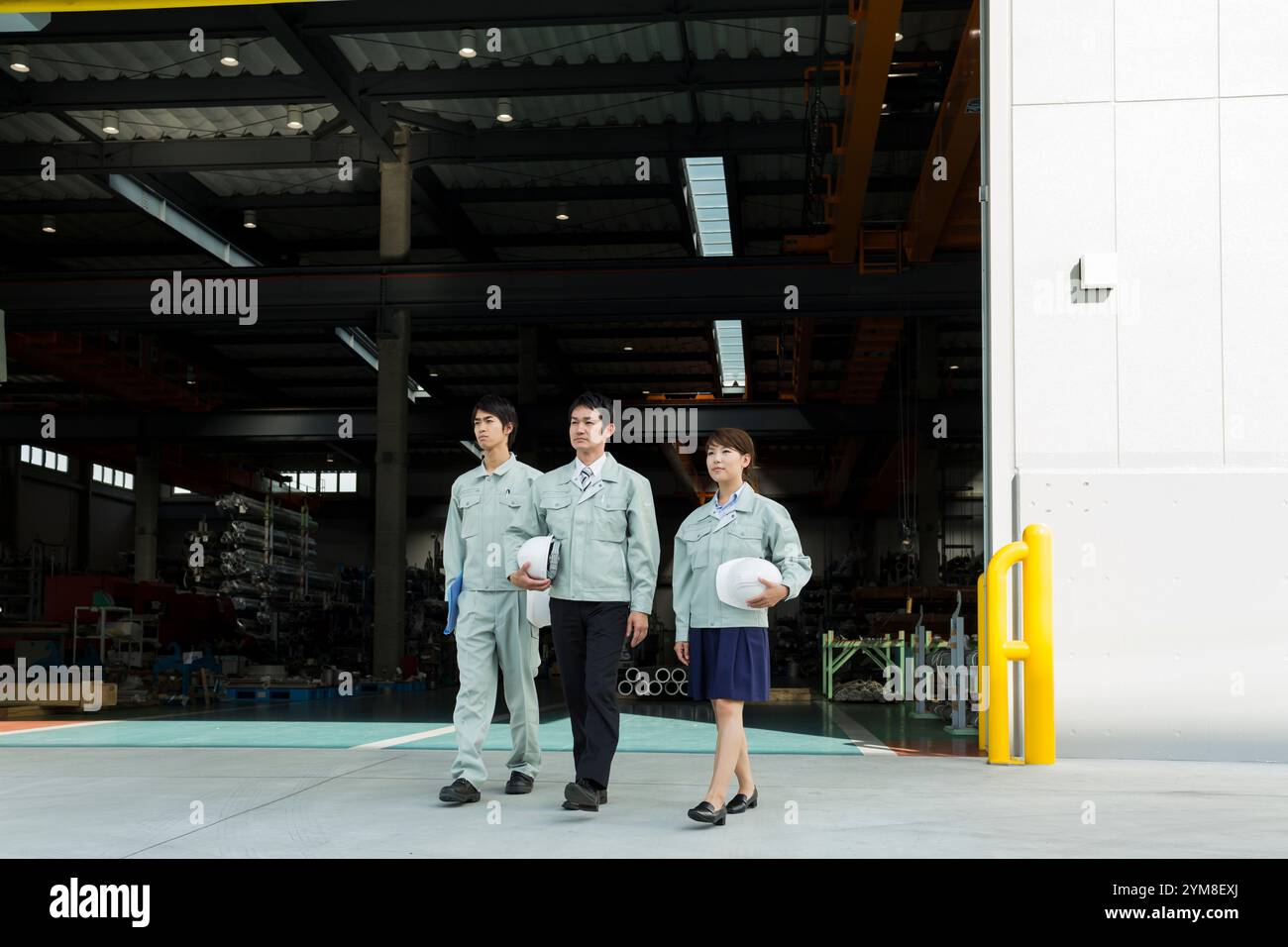 Male and female workers walking with helmets Stock Photo - Alamy