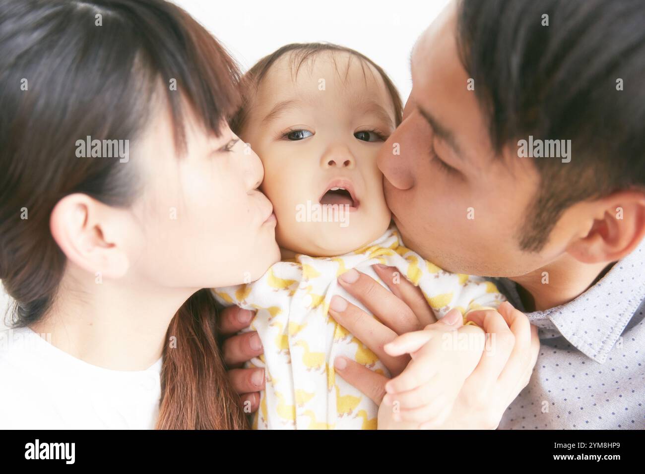 Parents kissing baby Stock Photo - Alamy