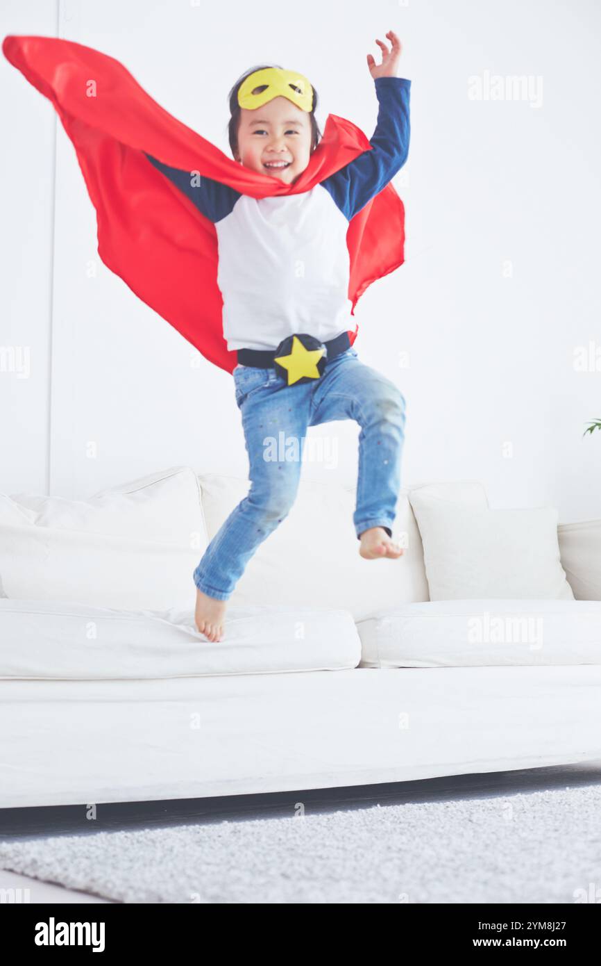 Little Superman jumping from the sofa Stock Photo - Alamy