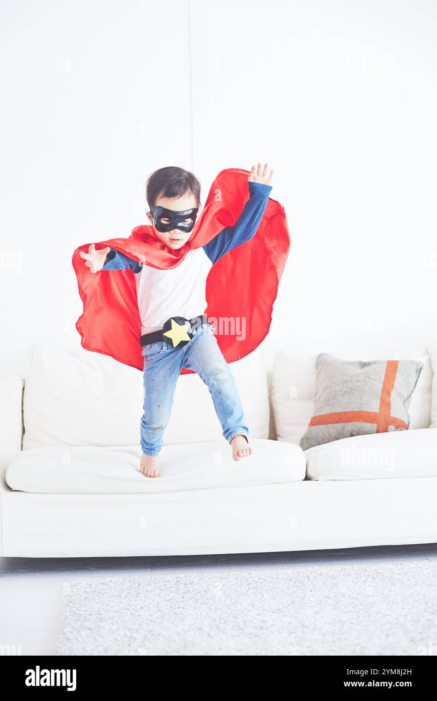 Little Superman jumping from the sofa Stock Photo - Alamy