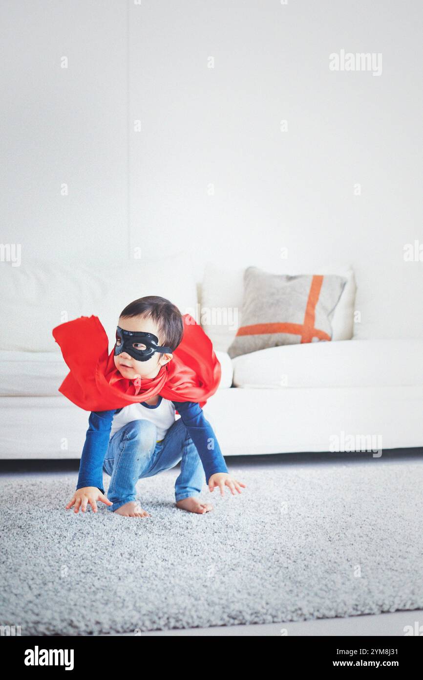 Little Superman jumping from the sofa Stock Photo - Alamy