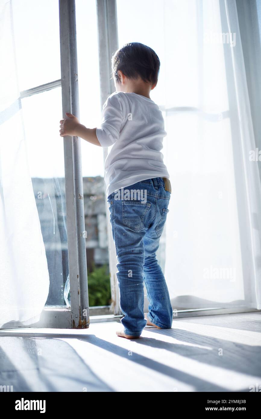 Boy trying to climb out of window Stock Photo - Alamy