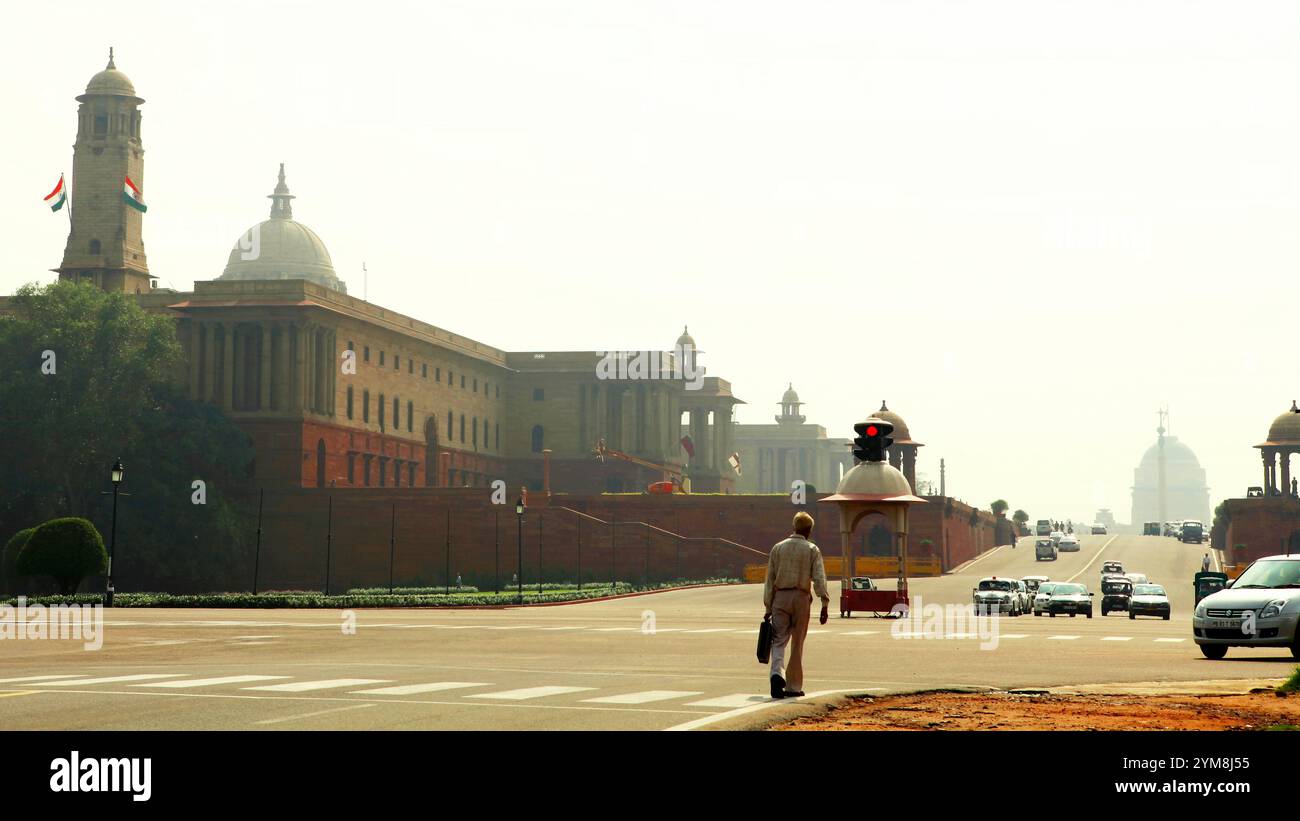 A man walking on Rajpath boulevard in a background of road traffic ...