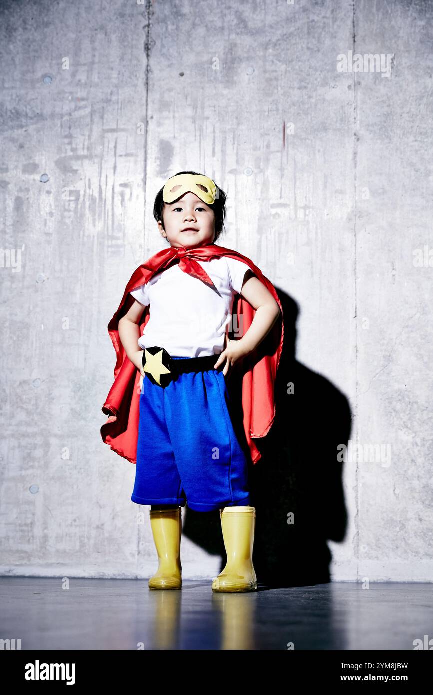 Hero boy posing in front of concrete wall Stock Photo - Alamy