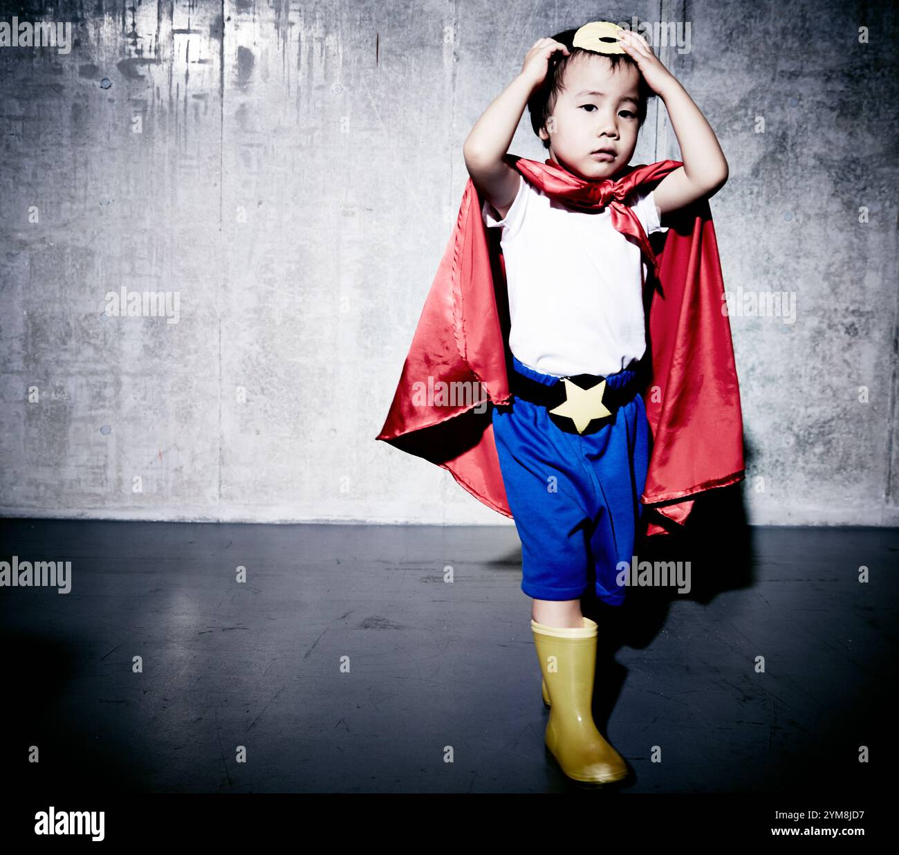 Hero boy posing in front of concrete wall Stock Photo - Alamy
