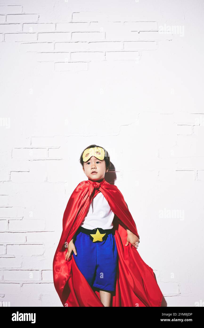 Hero boy doing victory pose in front of brick wall Stock Photo - Alamy