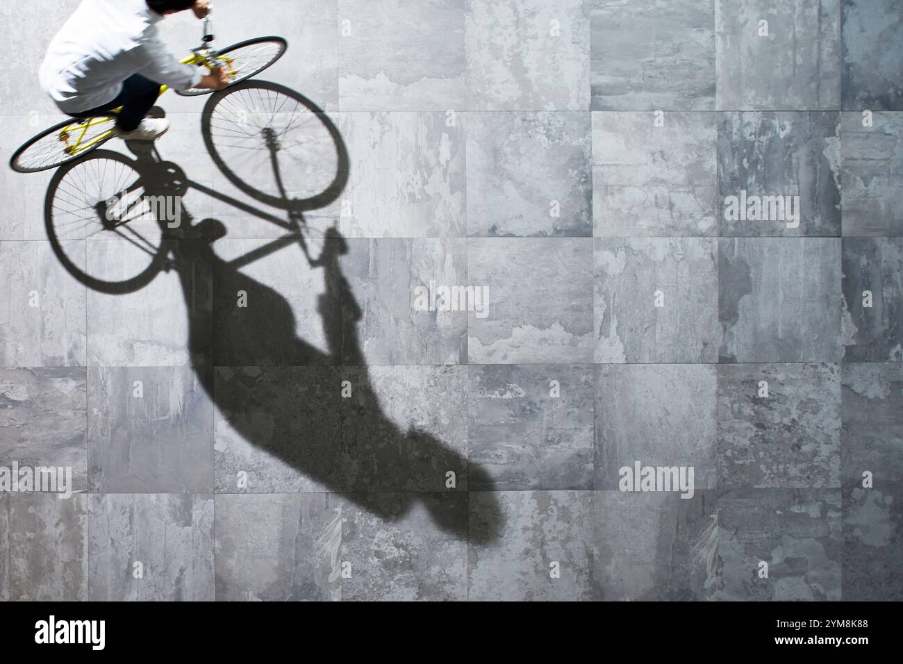 Man riding bicycle on stone floor with light shining through Stock ...