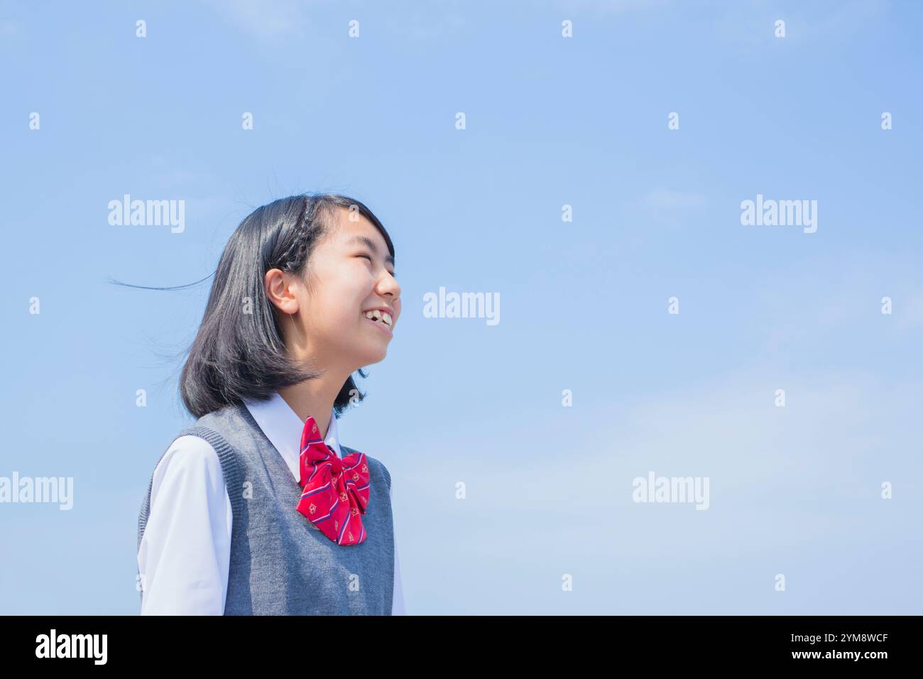 Blue sky and smiling female junior high school student Stock Photo - Alamy