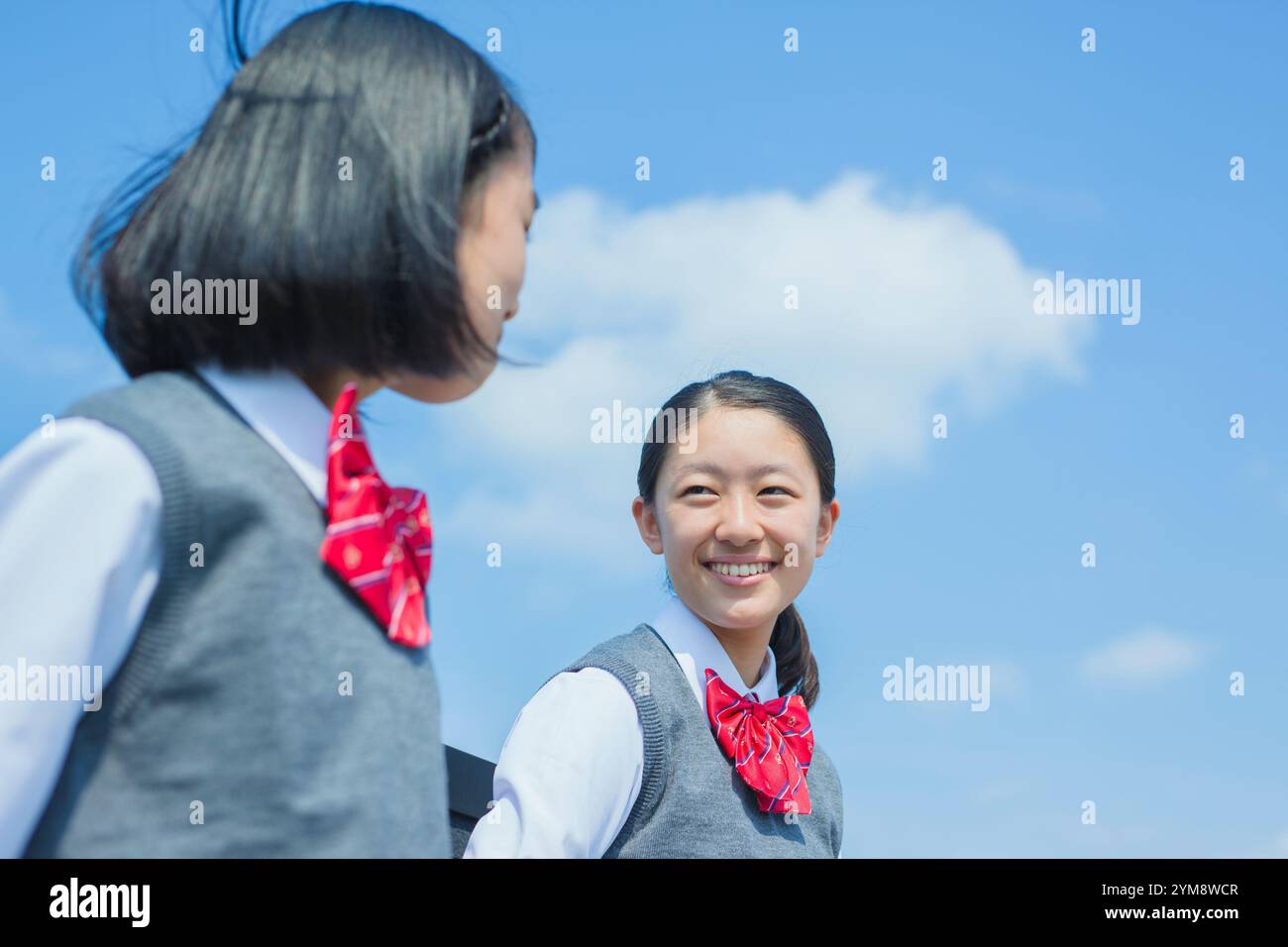 Blue sky and smiling female junior high school student Stock Photo - Alamy
