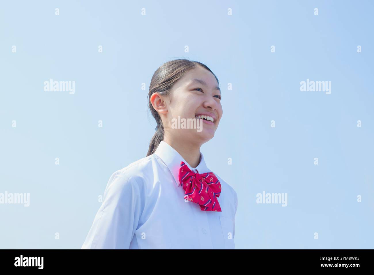 Blue sky and smiling female junior high school student Stock Photo - Alamy