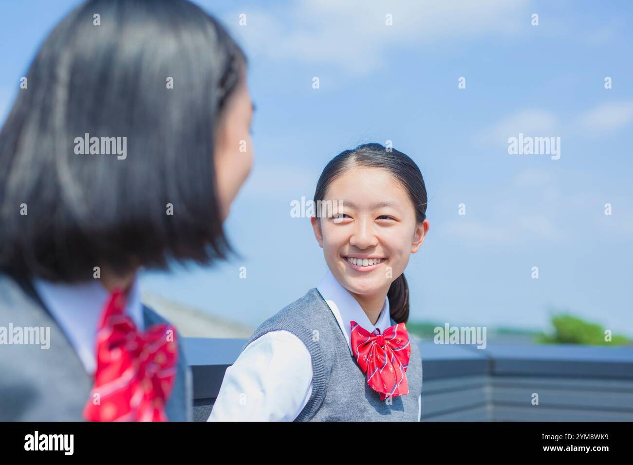 Blue sky and smiling female junior high school student Stock Photo - Alamy