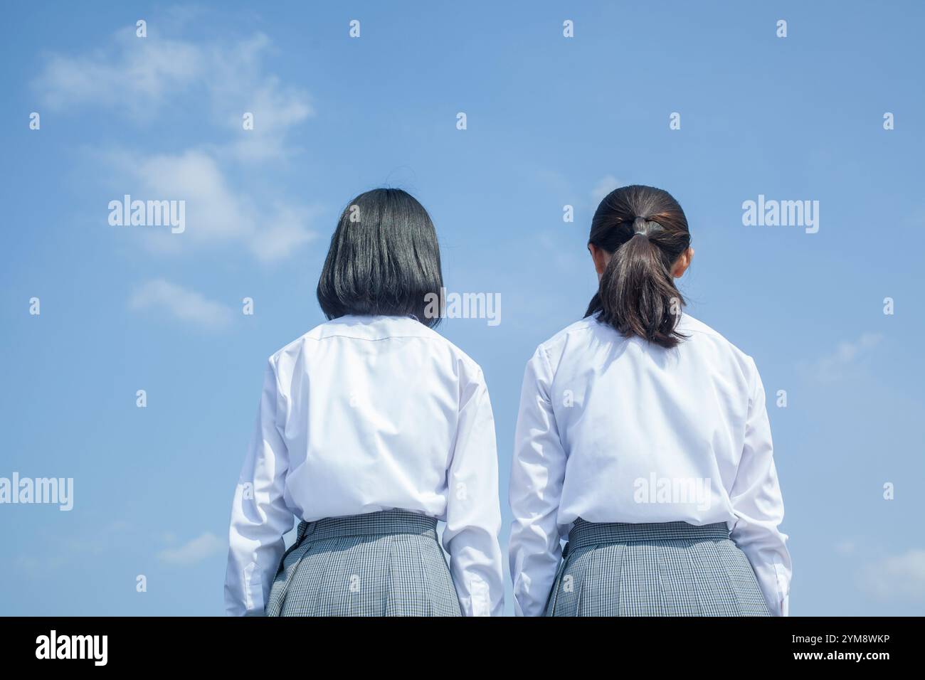 Blue sky and two female students back view Stock Photo - Alamy