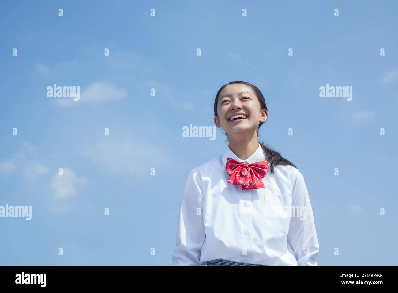 Blue sky and smiling female junior high school student Stock Photo - Alamy