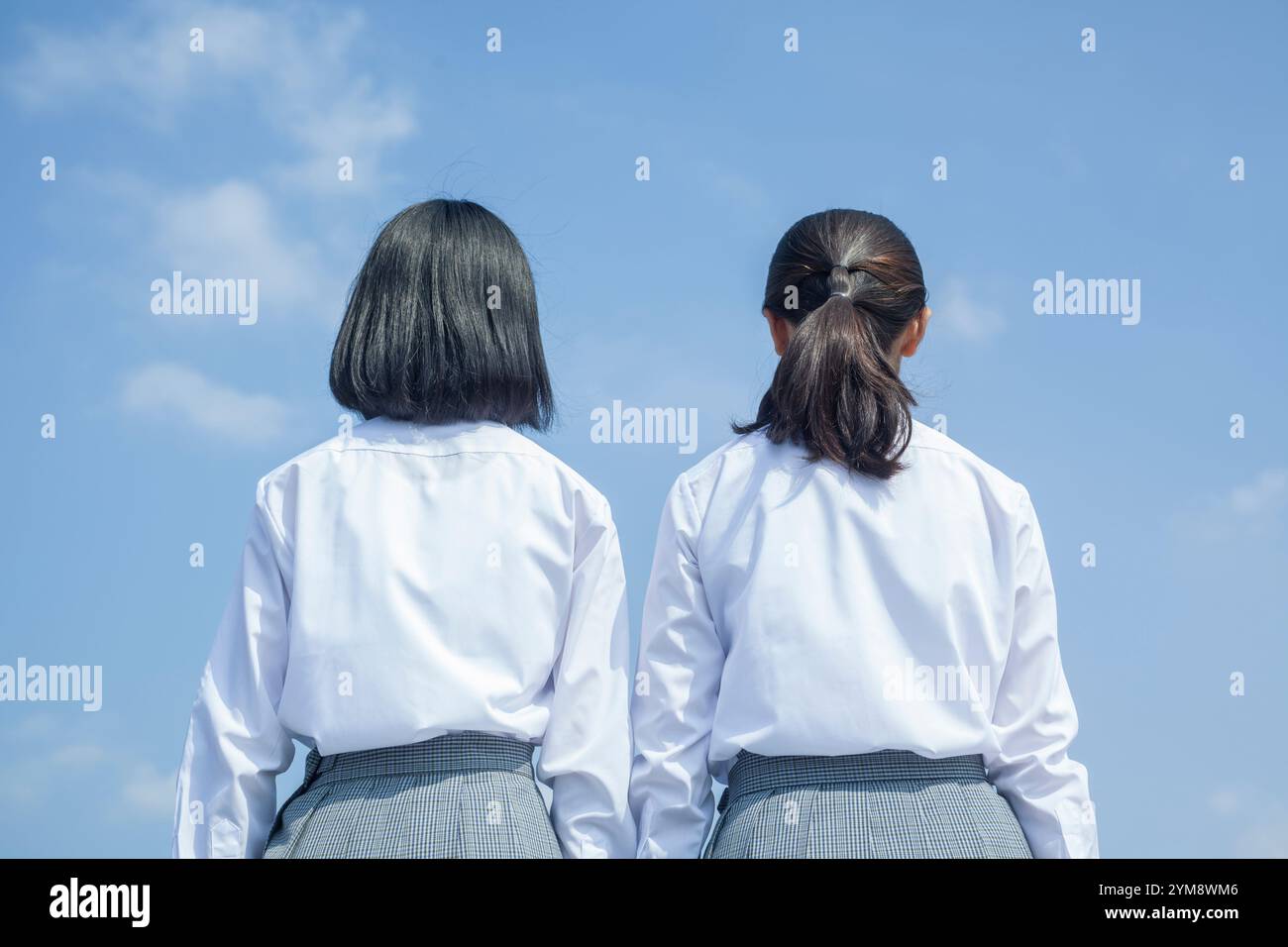 Blue sky and two female students back view Stock Photo - Alamy
