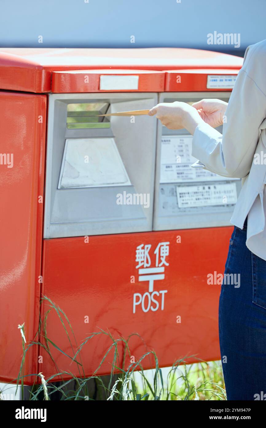 Young woman's hand putting an envelope in a mailbox Stock Photo - Alamy